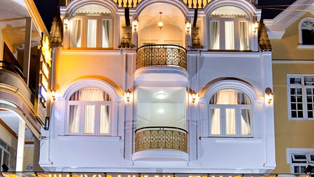 Um hotel com estilo arquitetônico tradicional, com várias sacadas e uma entrada bem iluminada.