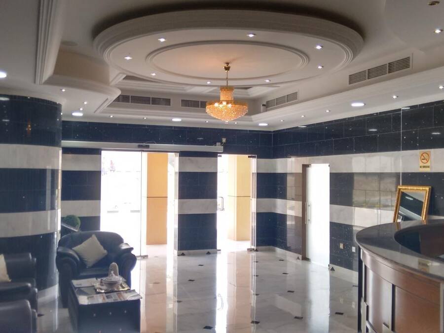 Um hall amplo com um candelabro, uma mesa de recepção e uma área de estar com sofá e poltronas.
