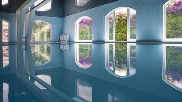 Quarto com janelas amplas refletindo um jardim com flores roxas.