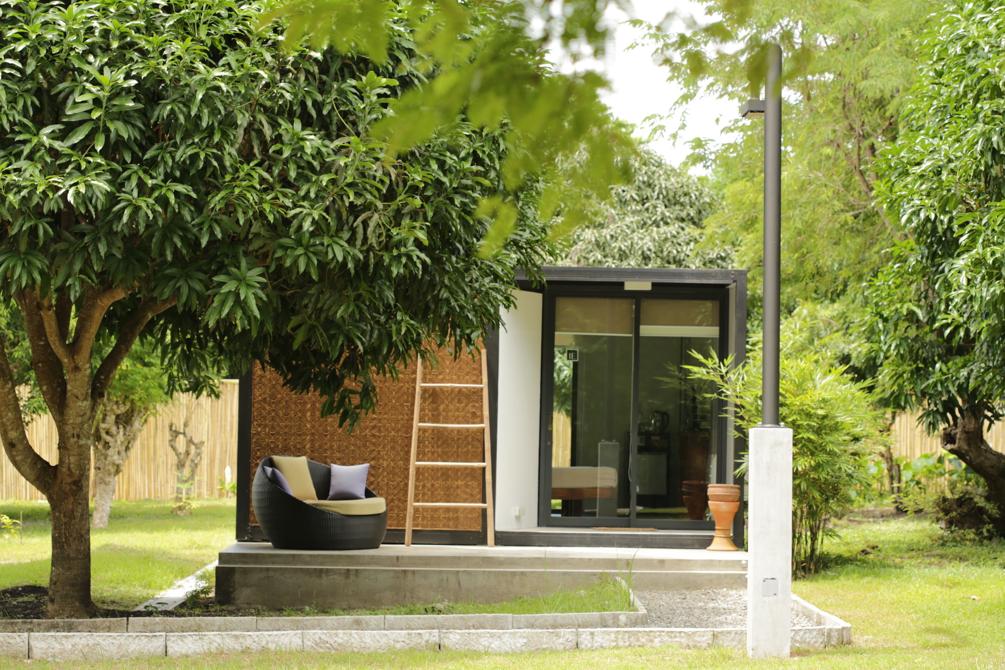 Área de estar moderna ao ar livre, com um banco acolchoado e uma escada que dá acesso a uma porta de vidro.