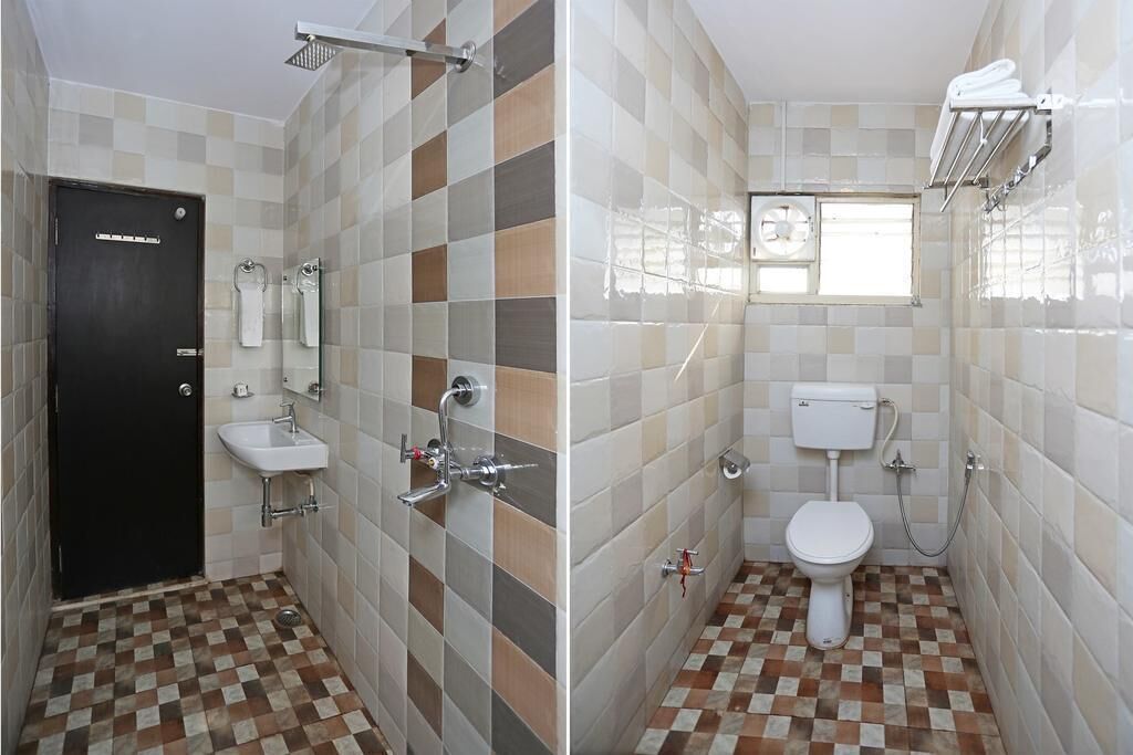 Casa de banho com porta preta, pia, sanita e chuveiro.