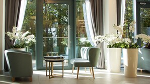 Decoração moderna com duas cadeiras, uma mesa e grandes vasos de plantas.