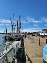Um cais com barcos atracados, céu claro e um edifício com uma placa.