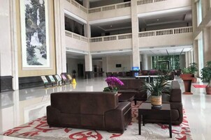 Um hall amplo com várias áreas de estar, uma mesa de recepção e uma grande obra de arte na parede.