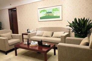 Sala de estar com sofá bege, mesa de centro de madeira e quadro de paisagem na parede.