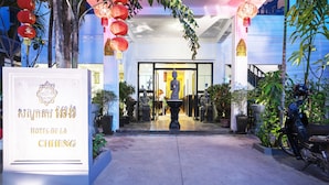Entrada do Hotel de la Chiheng com um arco de boas-vindas, vasos de plantas e uma motocicleta estacionada na frente.
