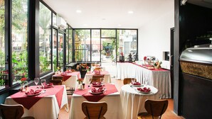 Restaurante com mesas montadas para refeições, amplas janelas e vista para o exterior.