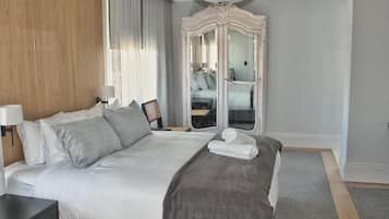 Quarto de hotel com uma cama grande, um guarda-roupa, um espelho e uma mesa de cabeceira.