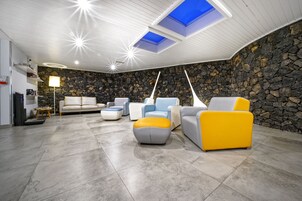 Uma sala de estar moderna com uma parede de pedra, um sofá e uma poltrona amarela.