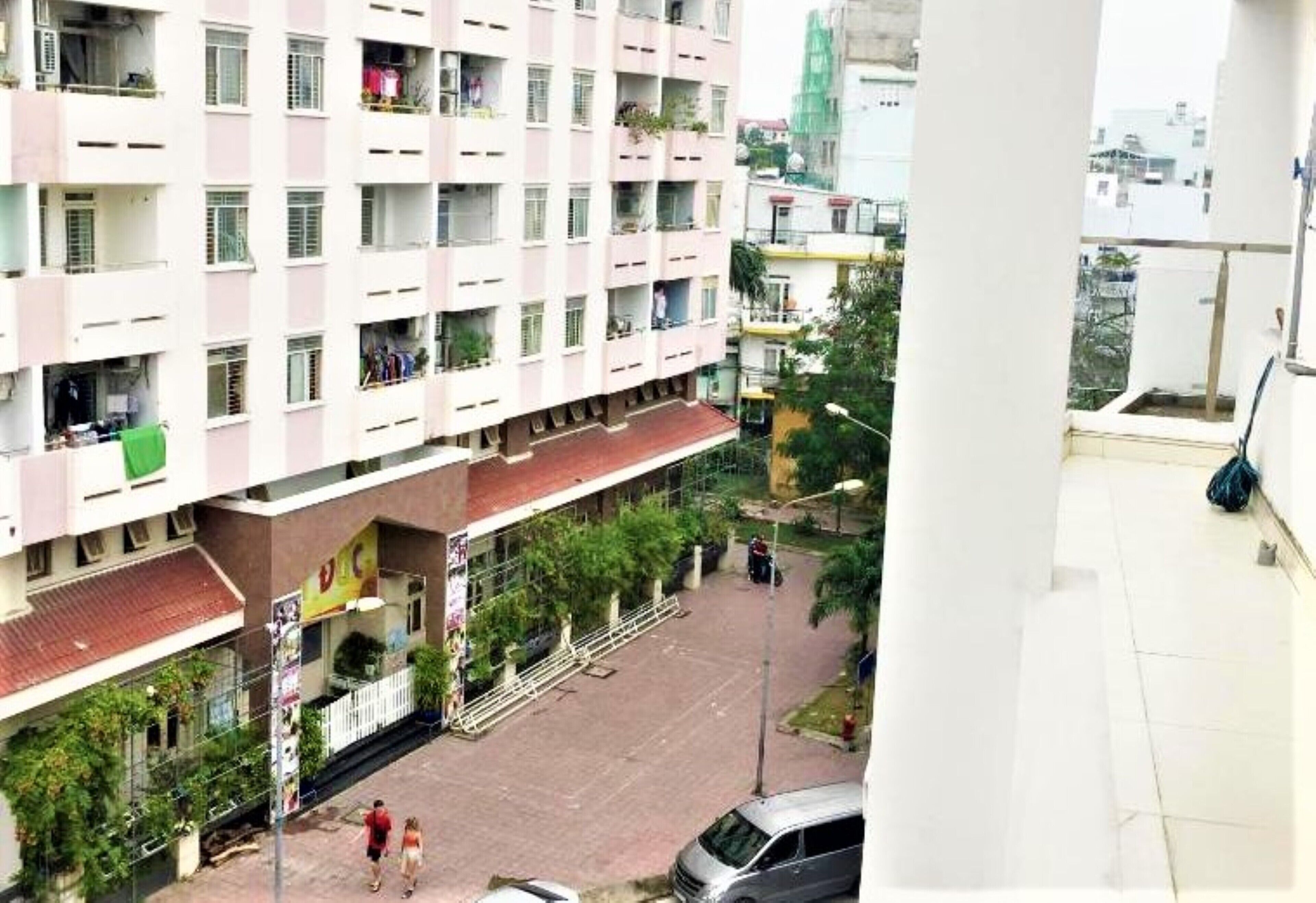 Um edifício com vários andares, varandas, entrada coberta e área ajardinada.