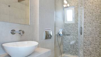 Uma casa de banho moderna com uma grande pia branca, uma cabine de duche com vidro e uma sanita.
