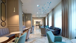 Um saguão de hotel com áreas de estar, piso de mármore e vista para a sala de jantar.