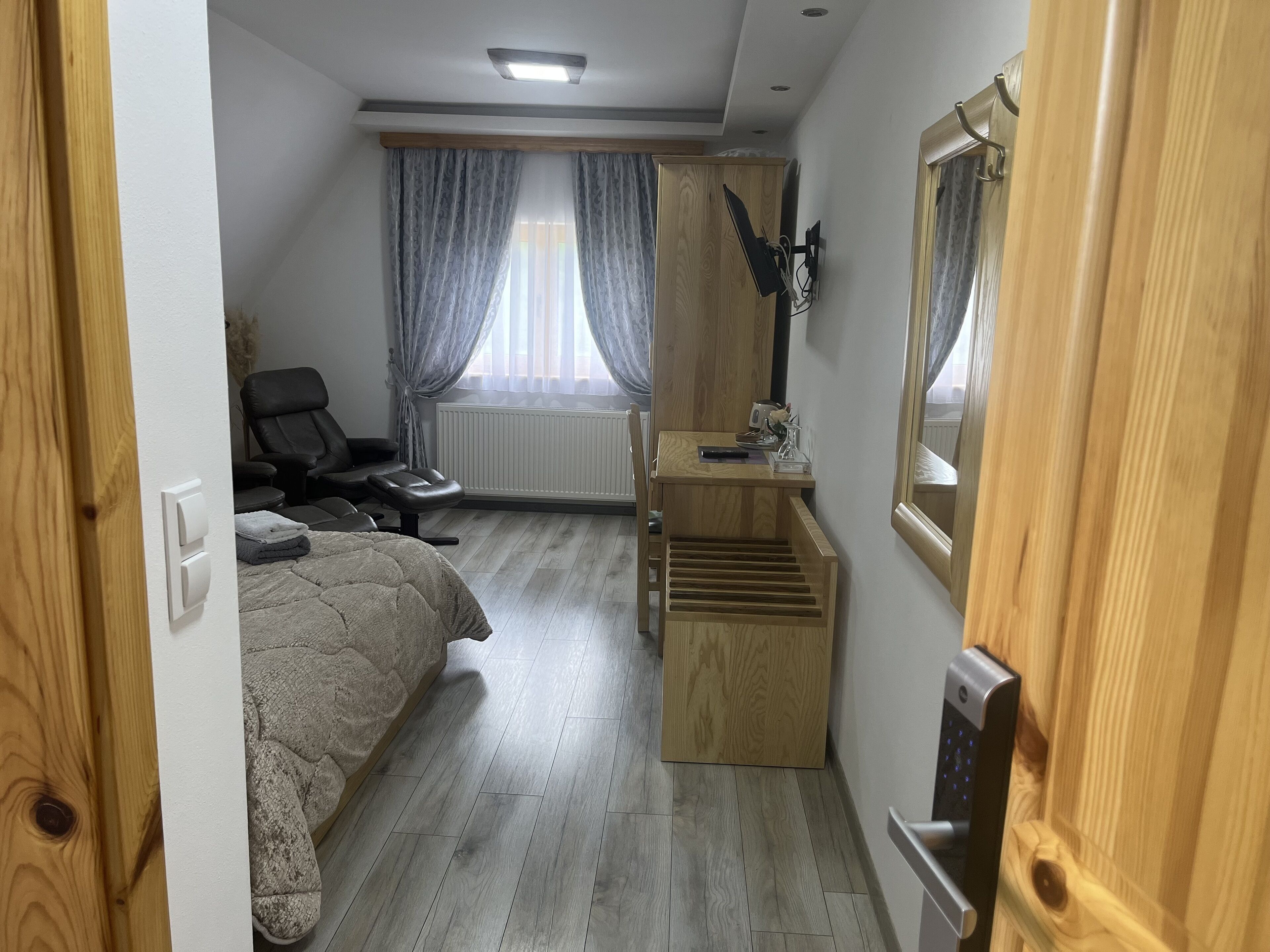 Um quarto com uma cama, uma escrivaninha, uma cadeira, um radiador e um espelho.