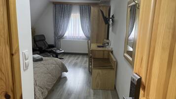 Um quarto com uma cama, uma escrivaninha, uma cadeira, um radiador e um espelho.