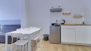 Uma cozinha compacta equipada com geladeira, cafeteira e uma pequena prateleira com copos.