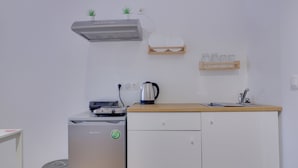 Uma cozinha compacta com máquina de lavar louça embutida, cafeteira e um pequeno cesto de lixo.