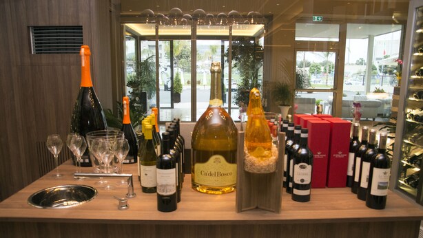 Uma área de bar com diversas garrafas de vinho e copos sobre um balcão de madeira.