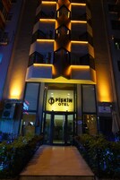 Entrada de hotel com design moderno, destacando uma placa visível e fachada bem iluminada.