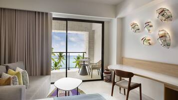 Quarto de hotel moderno com varanda, sofá, mesa de jantar e um banco.