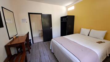 Quarto de hotel com cama, escrivaninha, cadeira e guarda-roupa.