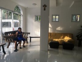 Um interior com um banco, um sofá e uma cruz na parede.