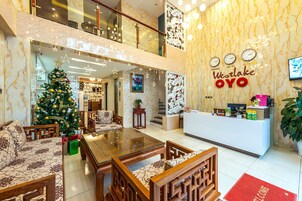 Um saguão de hotel com uma árvore de Natal, uma mesa de recepção e uma área de estar com uma mesa de vidro.