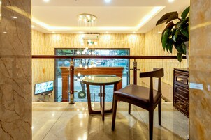 Um interior moderno com uma parede de mármore, uma mesa redonda de vidro, um banco de madeira e uma planta.
