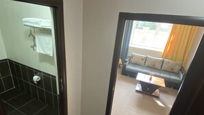 Quarto de hotel com banheiro, sofá e mesa de centro.