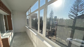 Um quarto com janelas amplas, parede de tijolos e chão de azulejos.