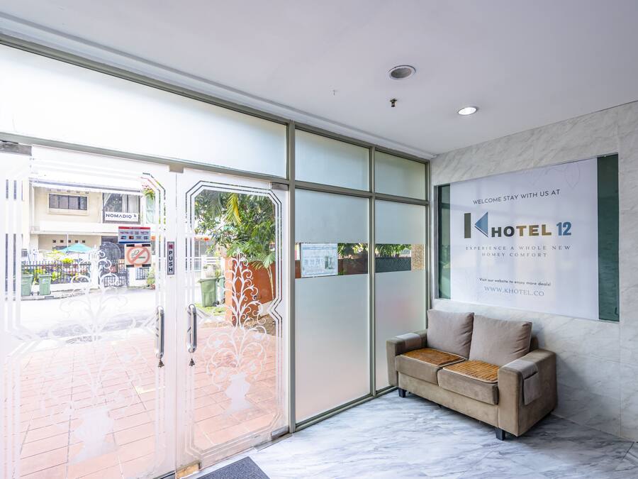 Uma área de recepção de hotel com porta de vidro, um sofá e um grande letreiro de boas-vindas.