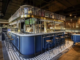 Uma área de bar com banquetas, balcão e variedade de garrafas.