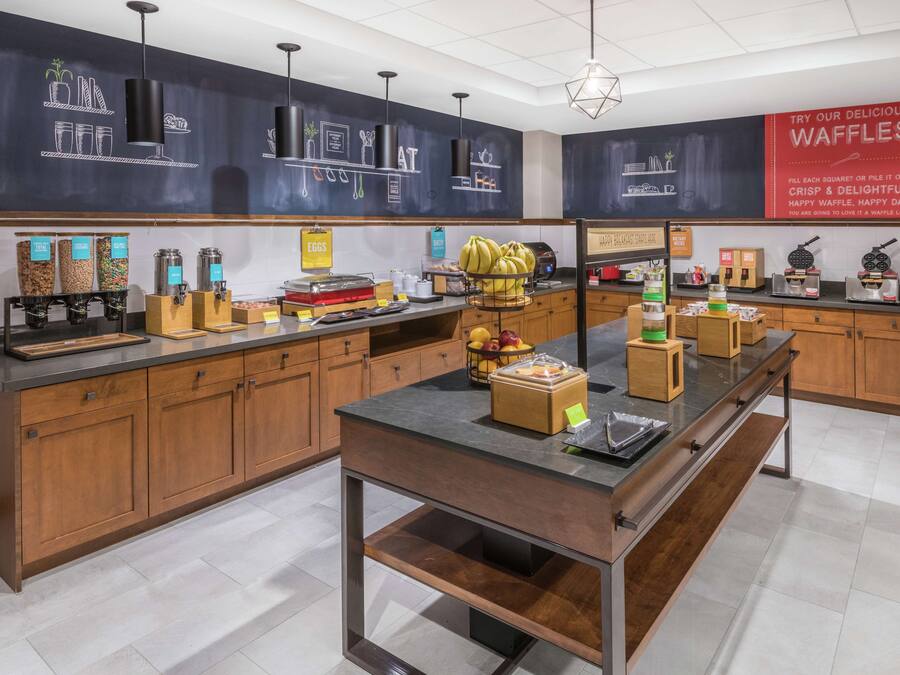 Uma cozinha com armários de madeira, uma ilha central e diversos eletrodomésticos e utensílios.