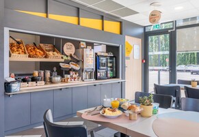 Um buffet de café da manhã com diversos alimentos e uma máquina de café.
