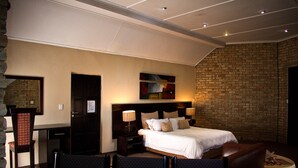 Quarto de hotel com cama, mesas de cabeceira, escrivaninha e cadeira.