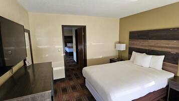 Quarto de hotel com cama grande, televisão de tela plana, escrivaninha e mesa de cabeceira.