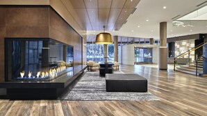 Um lobby moderno com lareira central, área de estar e escada.