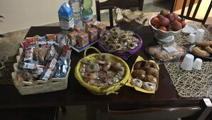 Uma mesa com diversos alimentos e bebidas, incluindo petiscos, doces e bebidas engarrafadas.