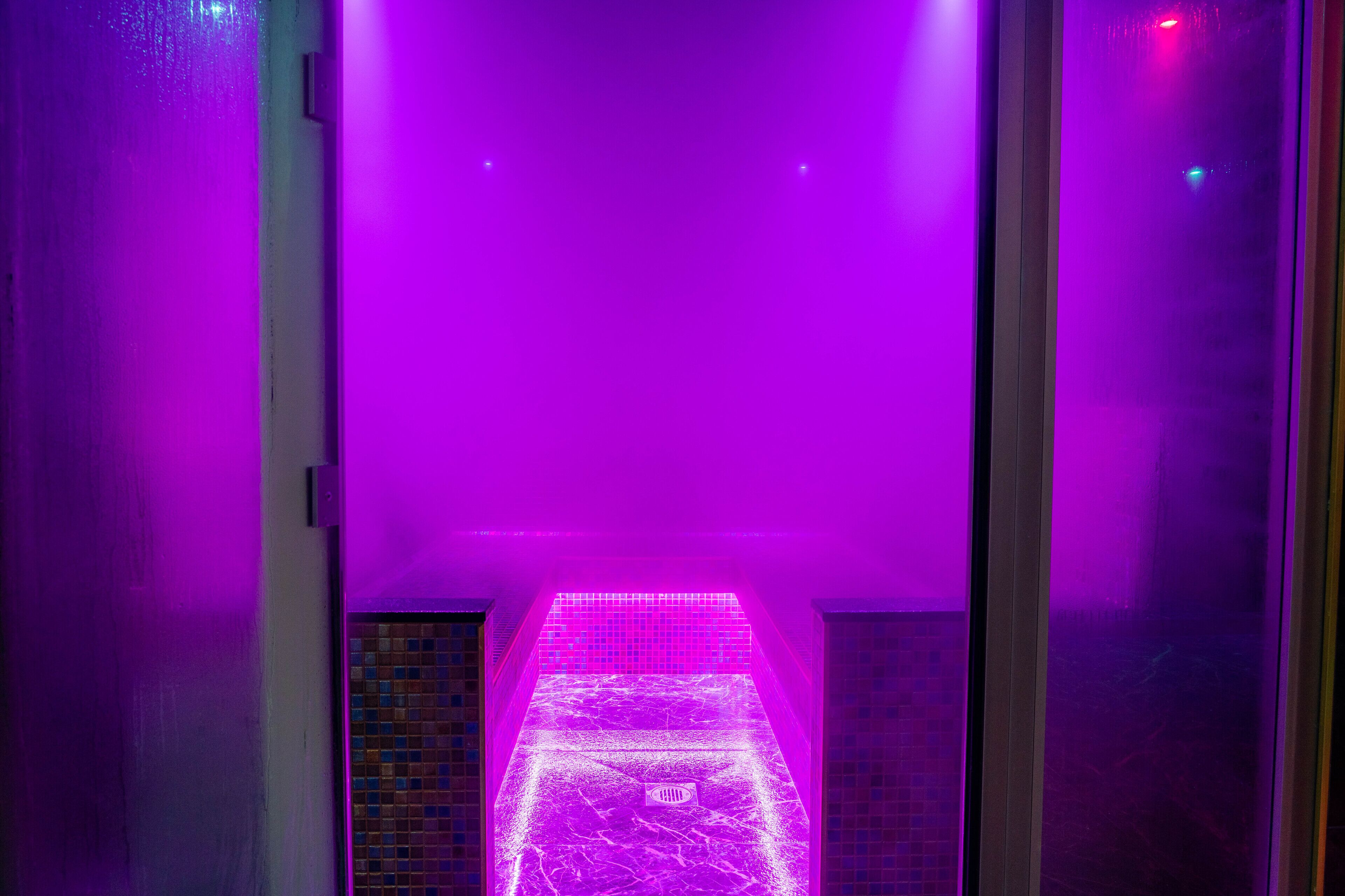 Um quarto com teto iluminado em roxo e chão de azulejos.