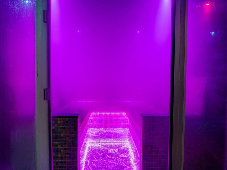 Um quarto com teto iluminado em roxo e chão de azulejos.