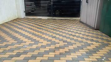 Uma área pavimentada com padrão xadrez, um portão preto e uma porta verde.