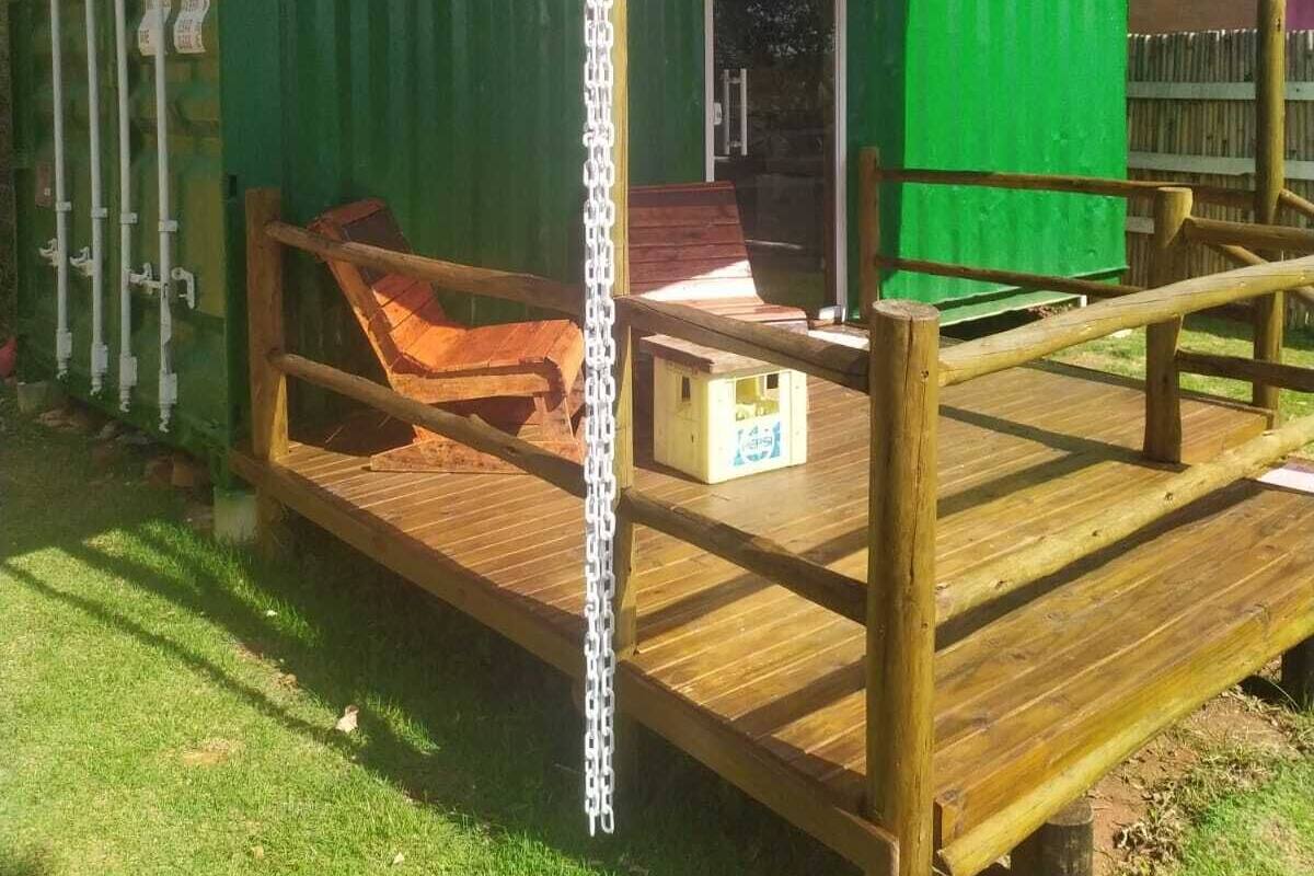 Uma pequena estrutura de metal verde com um deck de madeira e uma única porta.