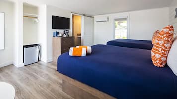 Quarto com duas camas, uma escrivaninha, um guarda-roupa e uma televisão.