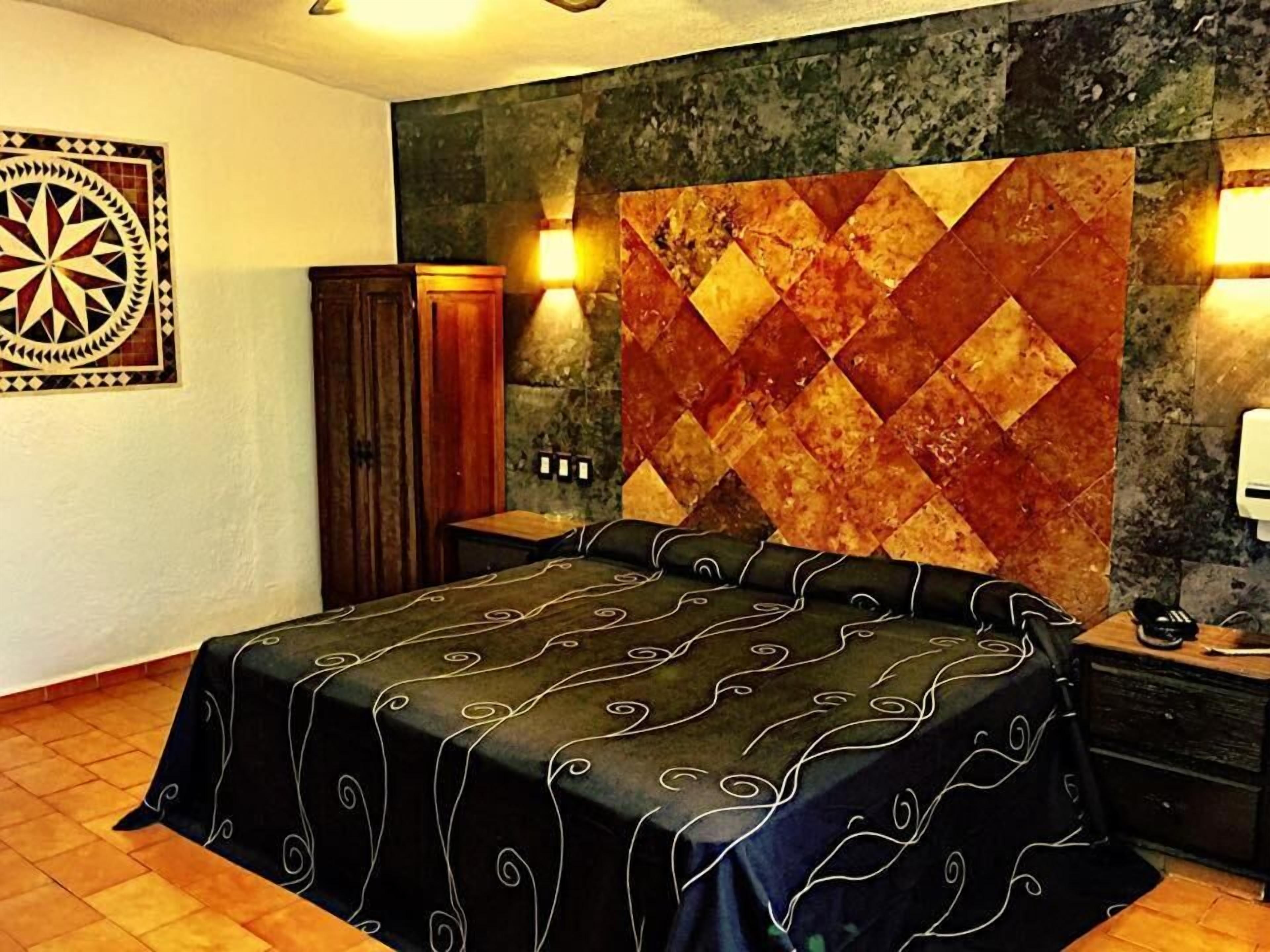 Quarto com uma cama, relógio na parede e painel decorativo.