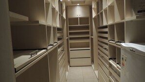 Um closet espaçoso com várias prateleiras e gavetas, uma geladeira branca e um luminário no teto.
