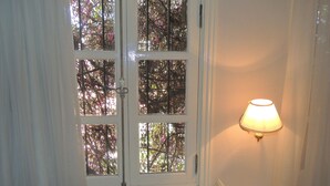 Um quarto com janela, luminária e cama.