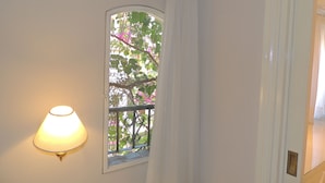 Um quarto com janela, luminária na parede e cortina.
