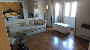 Uma sala de estar moderna com um sofá, um banquinho e uma mesa de centro de vidro.