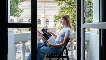 Uma pessoa sentada em uma cadeira perto de uma janela, lendo um livro.