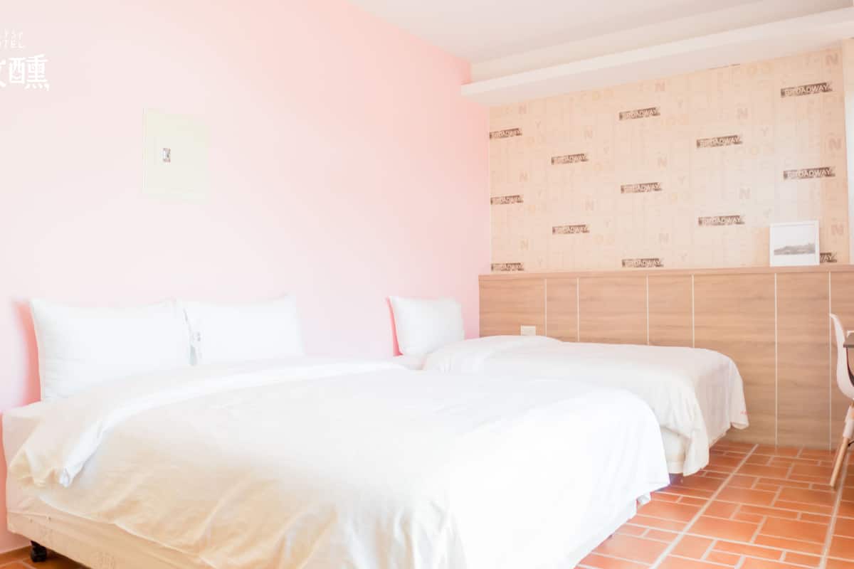 Quarto de hotel com duas camas, cabeceira de madeira, chão de azulejos e parede com a palavra 'Broadway' repetida.