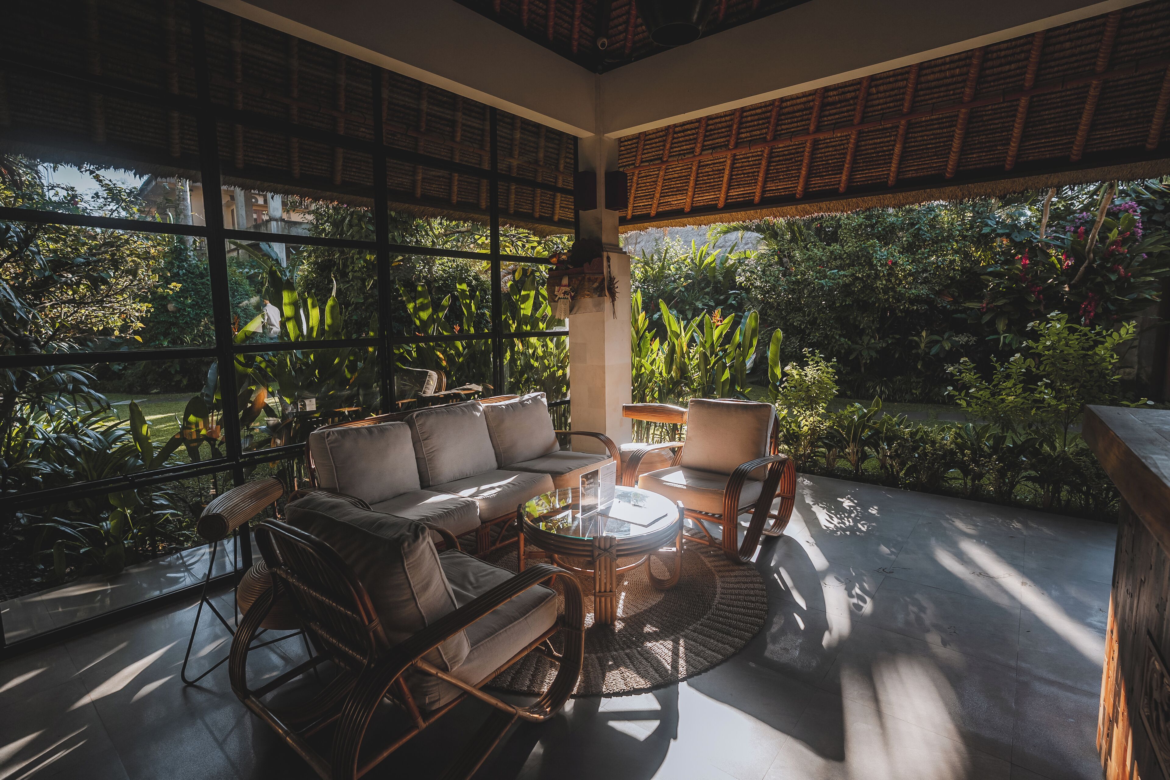 Um quarto amplo com uma grande janela, um sofá, uma mesa e cadeiras.